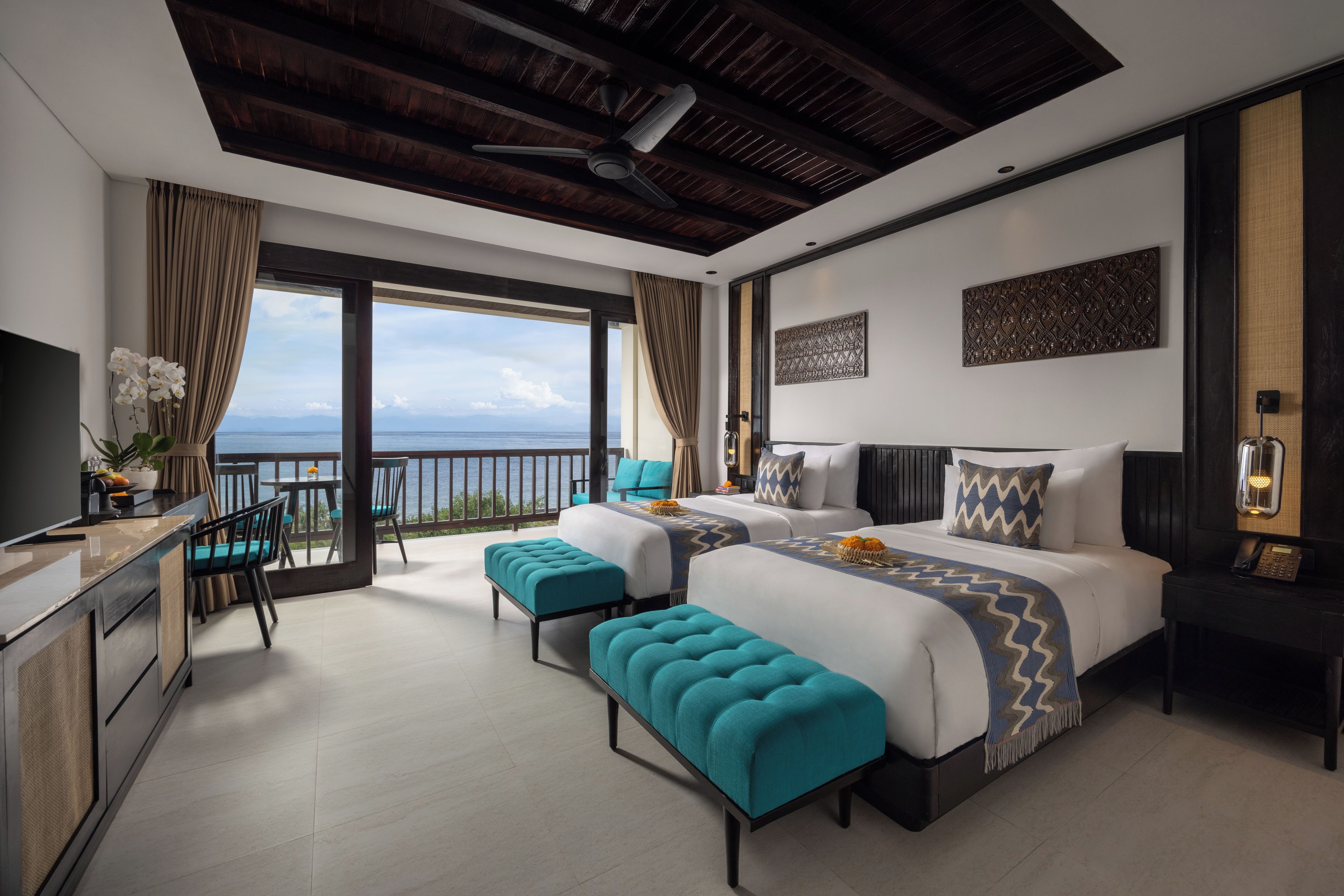Quarto de hotel moderno com varanda, duas camas, uma escrivaninha e televisão.
