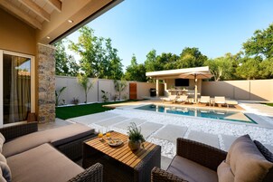 Um quintal com piscina, área de estar externa e um alpendre coberto.