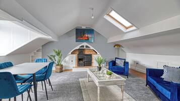 Um amplo loft com área de jantar, assentos, lareira e claraboia.