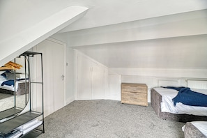 Quarto com cama beliche, guarda-roupa, cômoda de madeira e radiador.