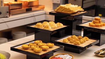 Buffet com diversos produtos de panificação expostos em suportes pretos.