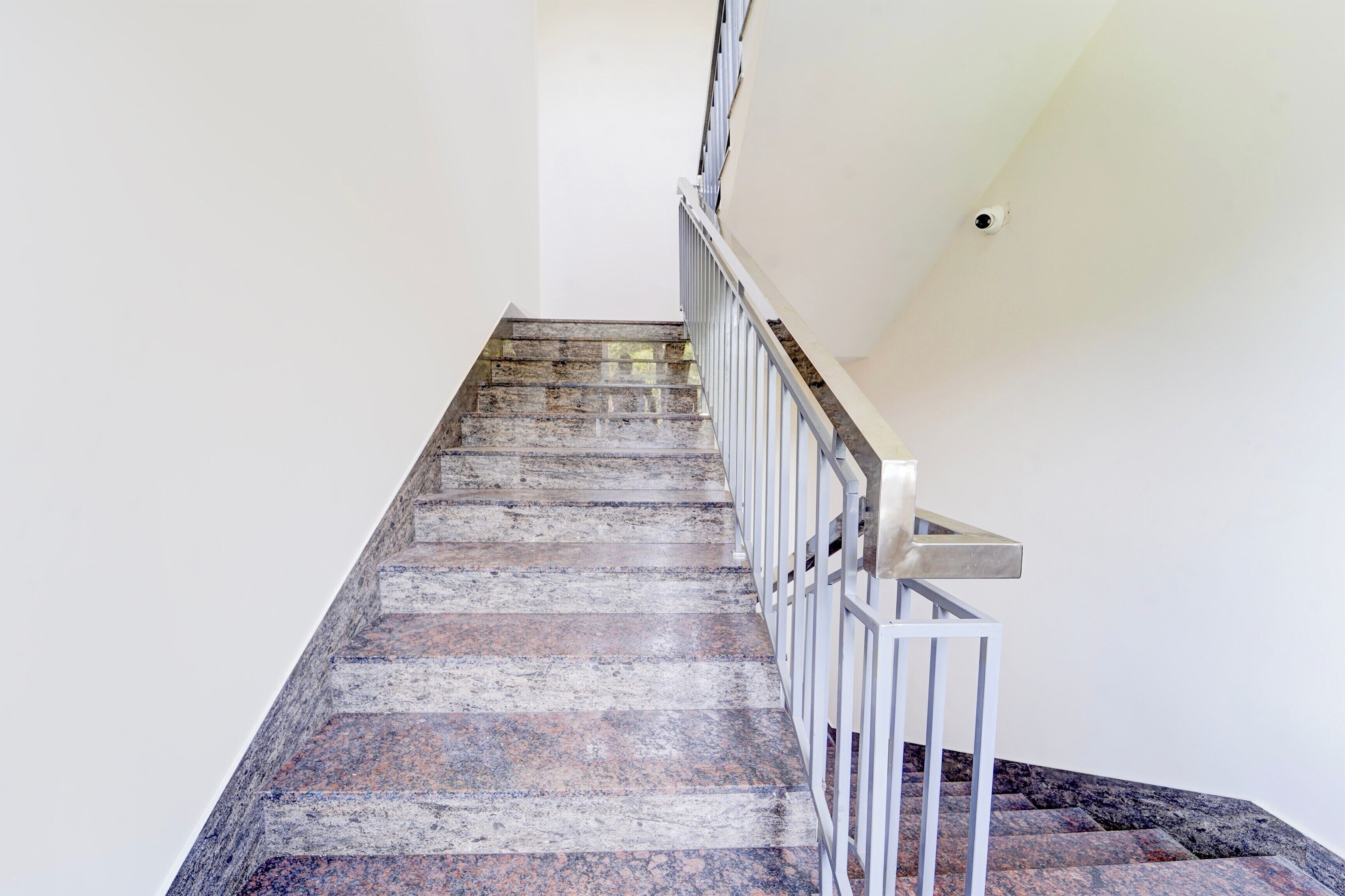 Uma escadaria com corrimão de metal e piso de pedra.