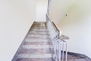 Uma escadaria com corrimão de metal e piso de pedra.