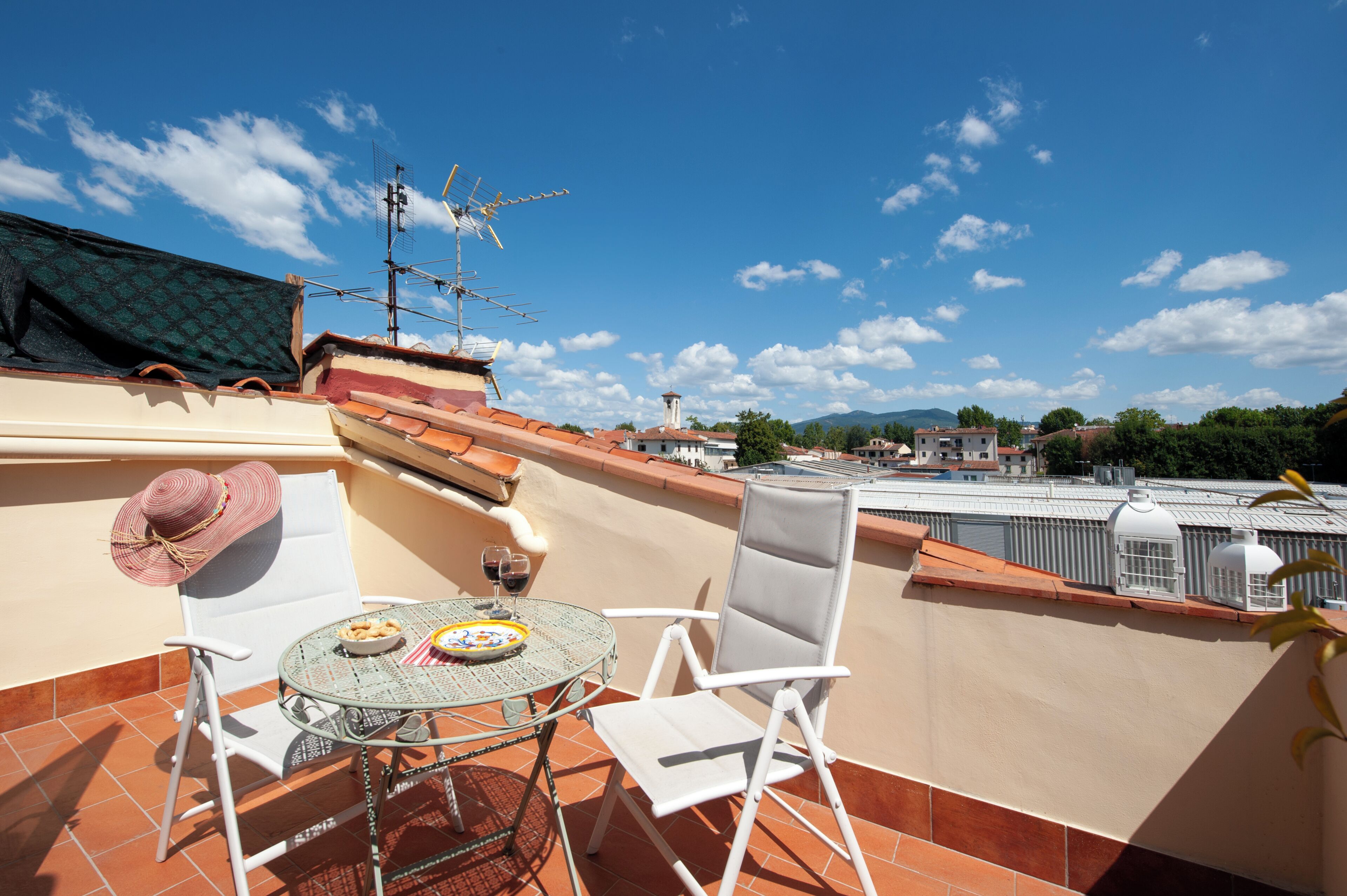 Um terraço com mesa e cadeiras, um chapéu e uma tigela de petiscos.
