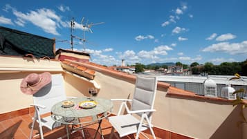 Um terraço com mesa e cadeiras, um chapéu e uma tigela de petiscos.