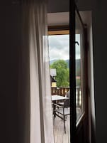 Quarto com vista para uma varanda, uma mesa e cadeiras.
