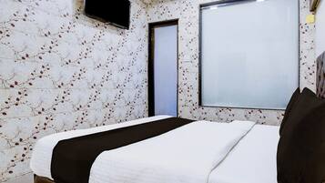 Um quarto com cama, televisão fixada na parede e janela com vista.