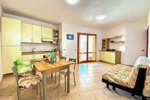 Um espaço compacto com área de refeições, cozinha compacta e uma cama.