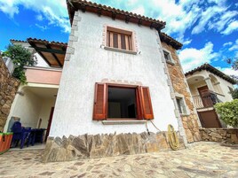 Um edifício de dois andares com fachada de pedra, uma varanda e uma janela com persianas de madeira.