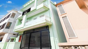 Um edifício de vários andares com fachada verde e branca, um toldo preto fechado no andar térreo e uma placa indicando um serviço da empresa.