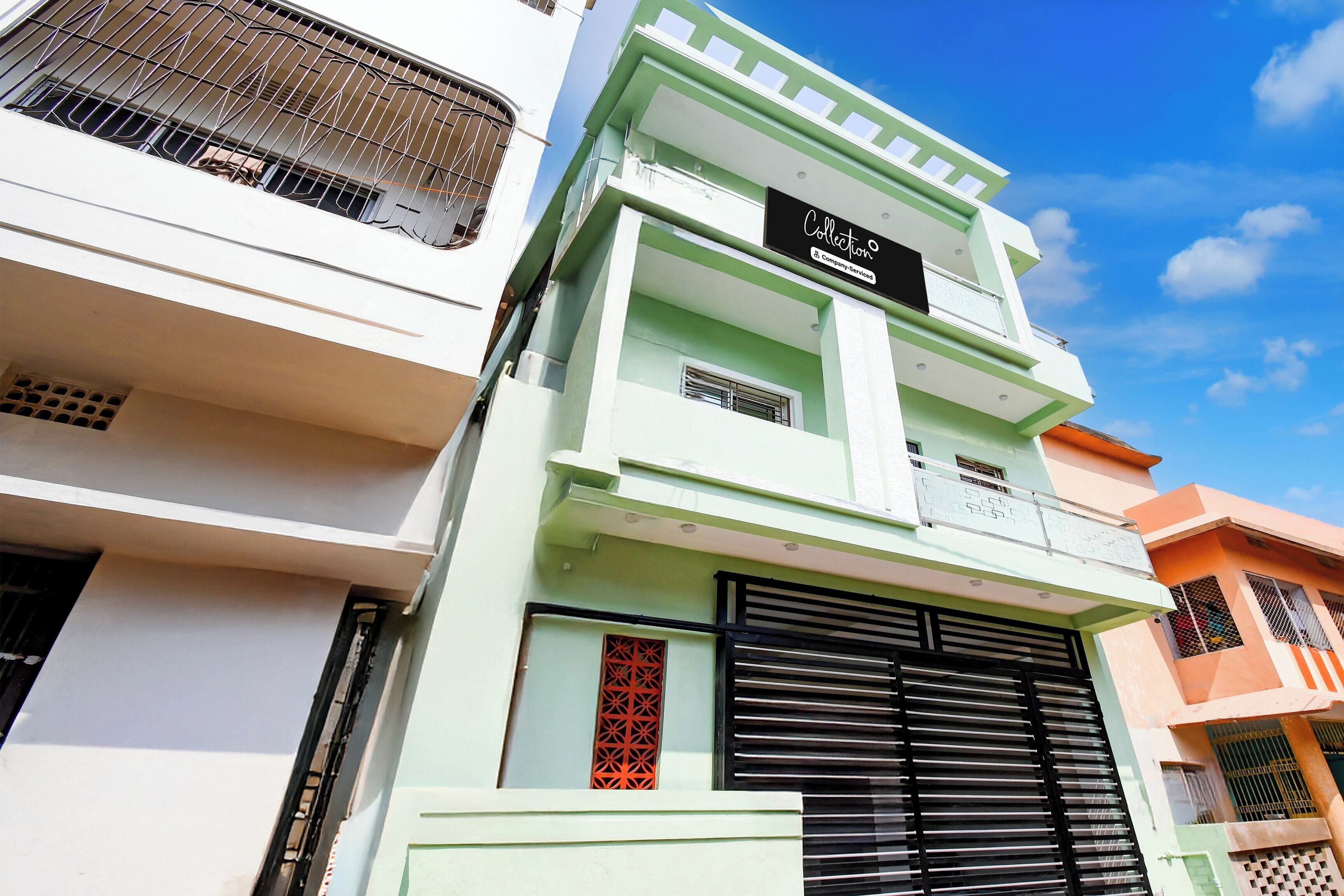 Um edifício de vários andares com fachada verde, porta de garagem preta e uma placa indicando um serviço da empresa.