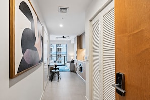 Um corredor com área de jantar, cozinha e vista para um edifício com varandas.