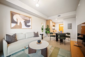 Uma sala de estar moderna com sofá, mesa de centro e área de jantar com cadeiras e mesa.