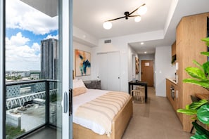 Quarto de hotel moderno com varanda, cama, escrivaninha e vista para a cidade.