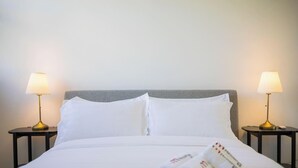 Quarto de hotel com uma cama, duas luminárias de cabeceira e uma mesa de cabeceira com controle remoto.