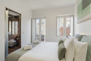 Um quarto com cama, banheiro e varanda.