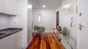 Cozinha moderna com bancada de mármore, área de refeições com duas cadeiras e piso de madeira.
