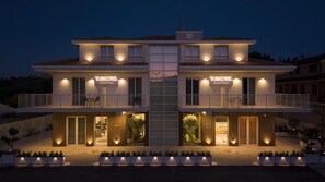 Um hotel de dois andares com entrada central, varandas e áreas de estar ao ar livre.