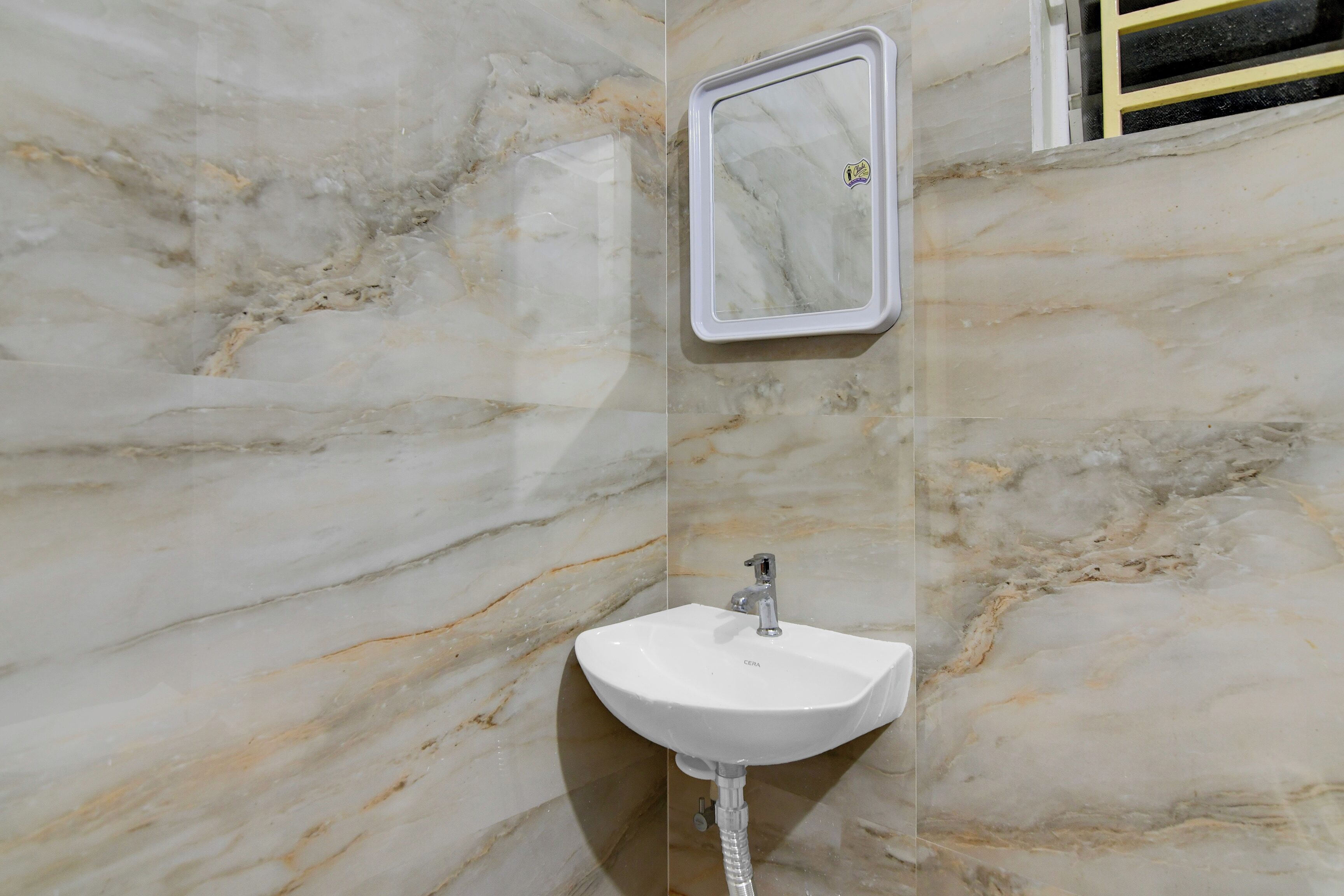 Uma casa de banho com parede de mármore, lavatório branco e espelho.
