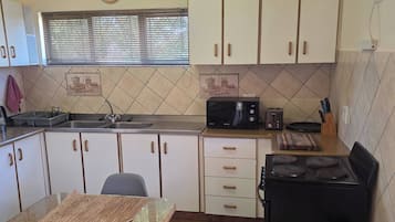 Uma cozinha compacta com armários brancos, micro-ondas, fogão e pia.