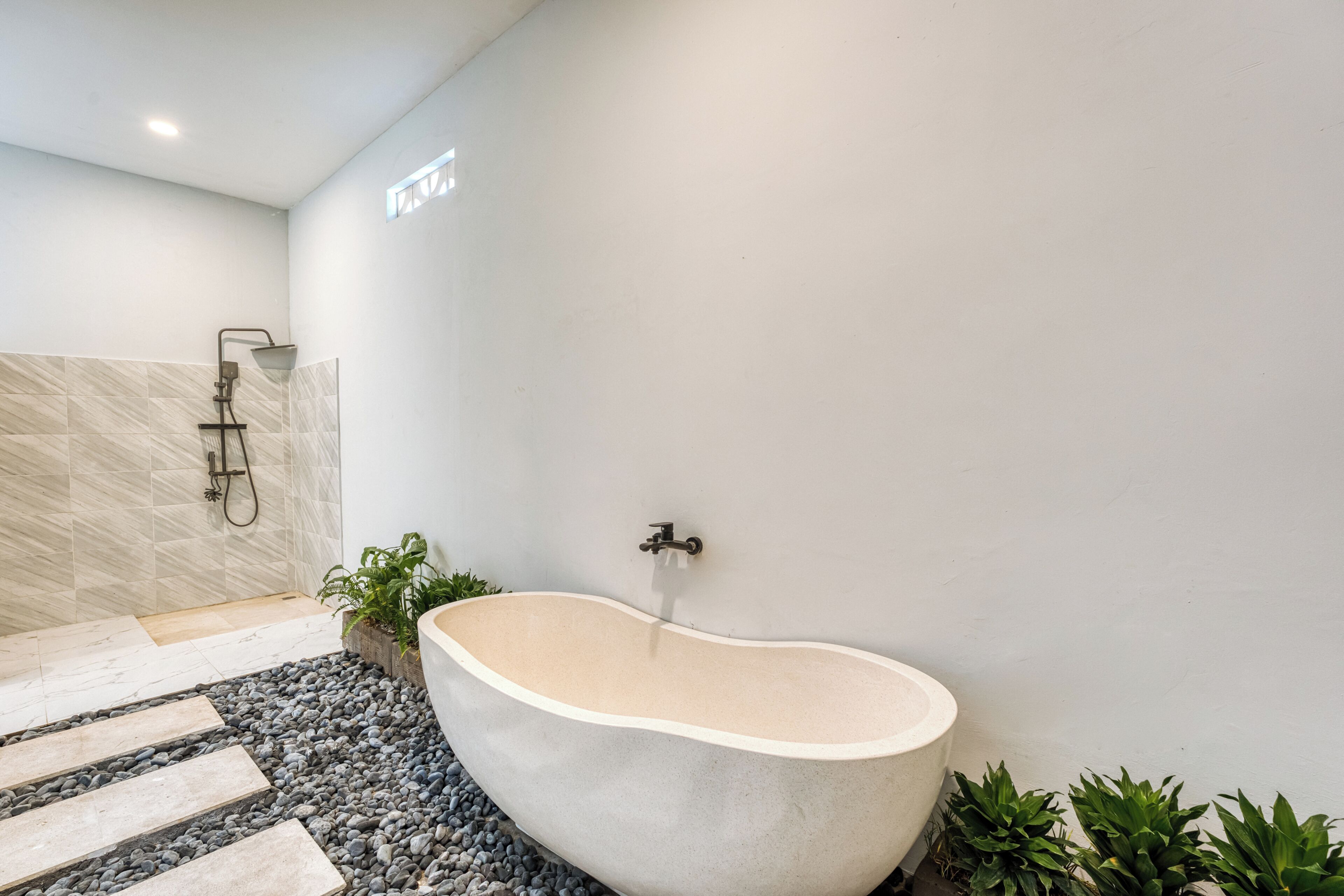 Uma casa de banho moderna com uma banheira independente, chuveiro e chão em mosaico.