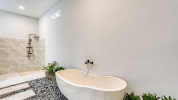 Uma casa de banho moderna com uma banheira independente, chuveiro e chão em mosaico.