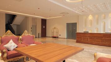 Um hall amplo com balcão de atendimento, escada e área de estar com sofás decorados.