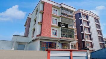 Um edifício residencial de vários andares com uma fachada de tijolos vermelhos marcante, varandas com guarda-corpos de metal e um letreiro indicando 'Collection' e 'Company-Serviced'.