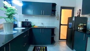 Uma cozinha moderna com armários escuros, micro-ondas, pia e geladeira.