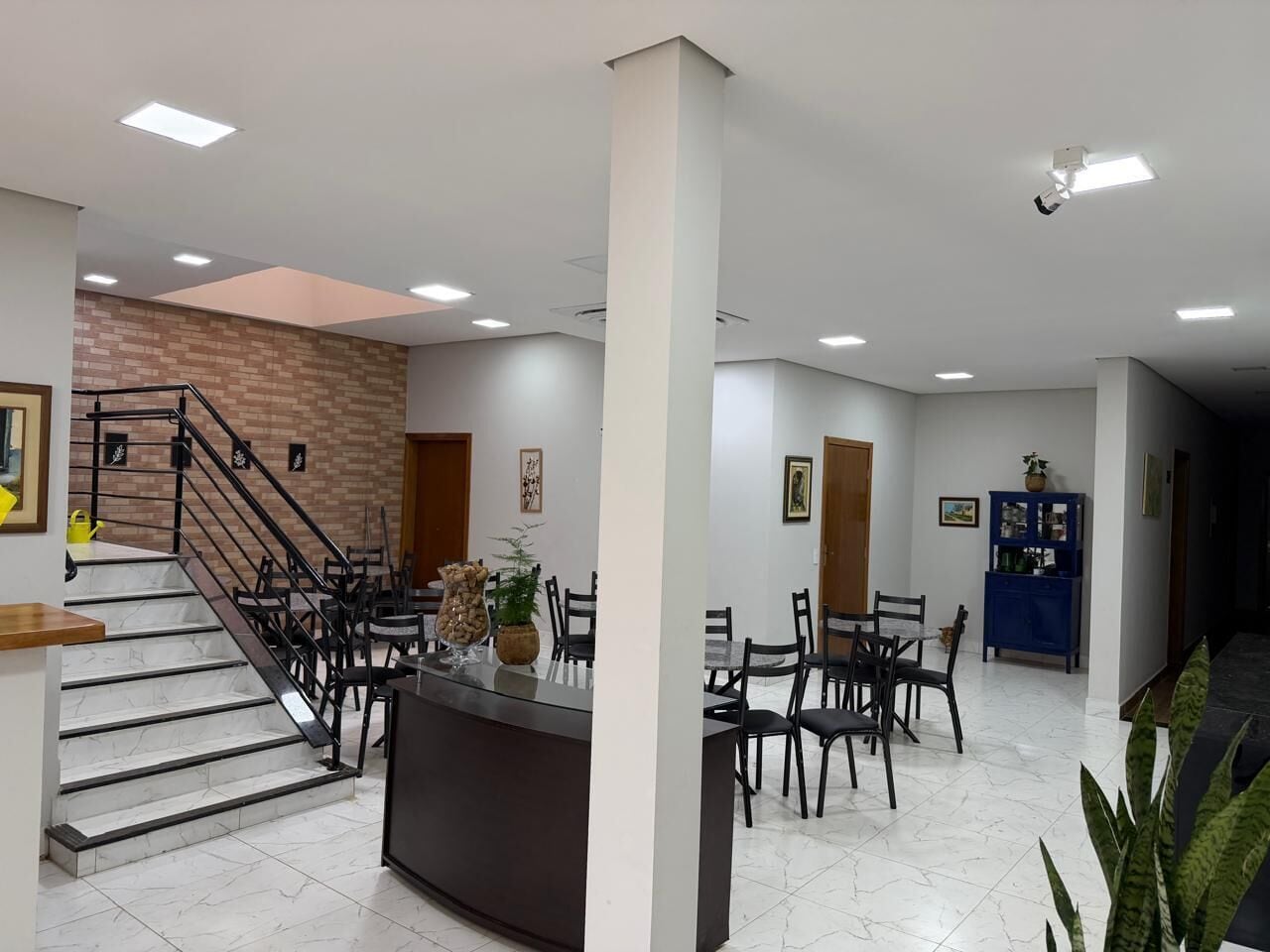 Um hall de hotel com escadas, balcão de recepção e área de refeições.
