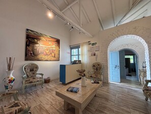 Um quarto com piso de madeira, um quadro na parede, uma porta azul e um arco branco.