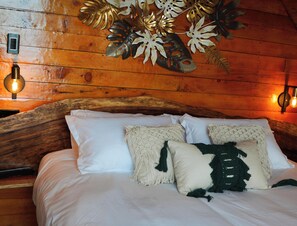 Uma cama de madeira com roupa de cama branca e almofadas decorativas.