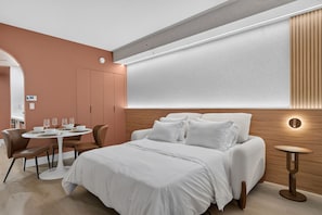 Quarto de hotel moderno com uma cama, uma mesa de jantar redonda e cadeiras.