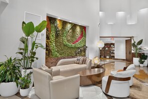 Um hall moderno com um sofá bege, uma mesa de centro e plantas em vasos.