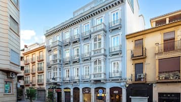 Um edifício de vários andares com estilo arquitetônico clássico, com varandas e grandes janelas.