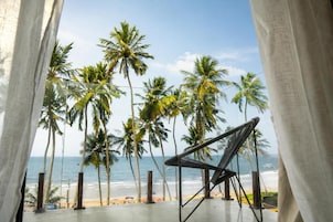 Vista da praia com palmeiras e uma cadeira.