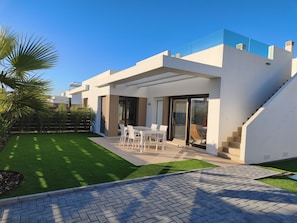 Uma casa moderna com varanda, escadas e um gramado bem cuidado.