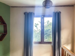 Um quarto com janela, luminária no teto e corrimão de madeira.