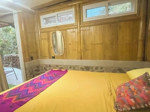 Um quarto com cama, espelho e janela.