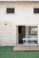 Um edifício com deck de madeira, porta de correr de vidro que dá para o interior e uma pequena área de estar ao ar livre.