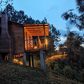Uma cabana de madeira com varanda, rodeada por árvores.