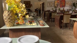 Disposição de buffet com diversos pratos e um vaso decorativo de flores amarelas.