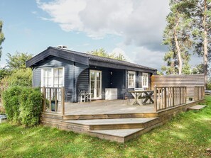 Uma cabana com varanda, área de estar externa e pequeno alpendre.