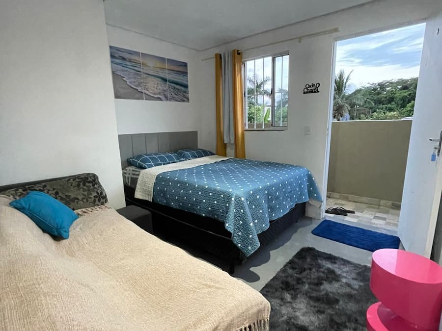 Quarto com duas camas, janela, porta e uma pequena varanda.
