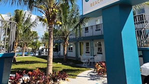 A Seaside Beach Resort sign with a clear view of the resort's building and surrounding palm trees.