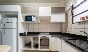 Uma cozinha compacta com geladeira, micro-ondas, fogão, forno e pia.
