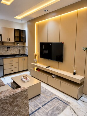 Cozinha moderna com eletrodomésticos embutidos, televisão de tela plana e painel de fundo de mármore.