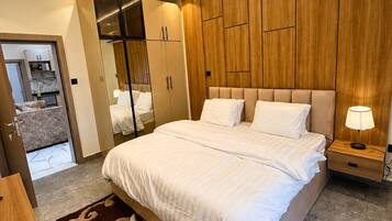 Quarto moderno com cama grande, parede de painéis de madeira, armário embutido e ar condicionado.