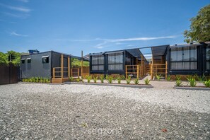 Um edifício moderno com vários quartos, um caminho de acesso de cascalho e pequenas plantas.