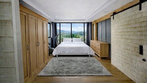 Quarto com uma cama grande, guarda-roupa de madeira e vista para o exterior.